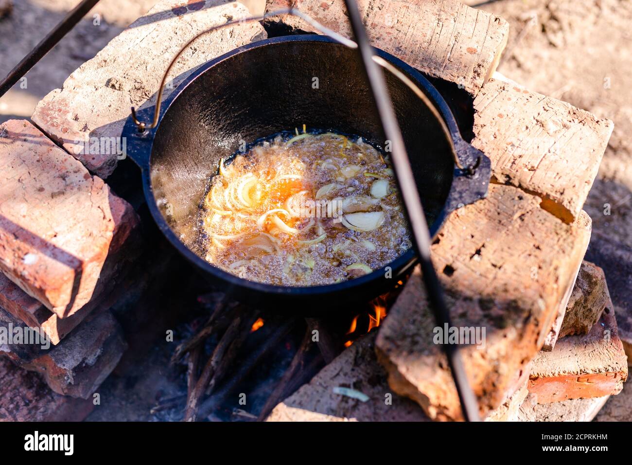 Preparation of pilaf in a cauldron on an open fire Stock Photo - Alamy