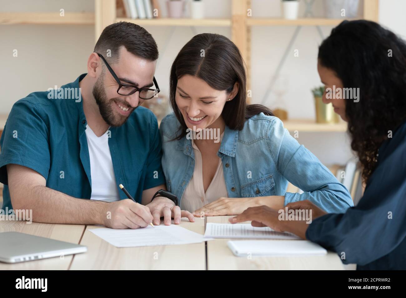 Happy young married couple signing contract, making successful deal ...