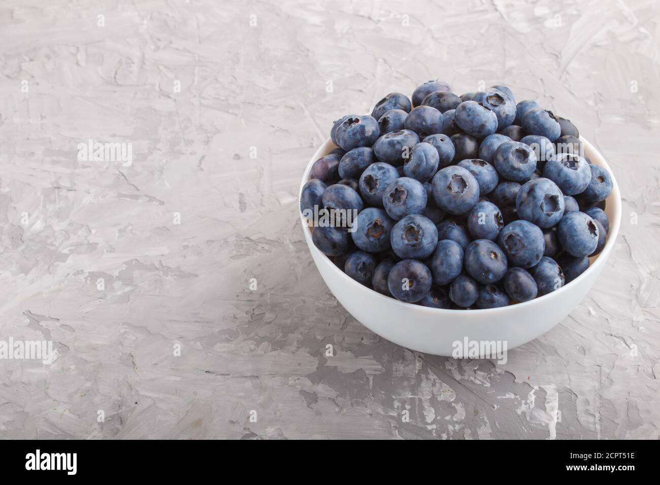 Fresh blueberry in white bowl on gray concrete background. side view ...