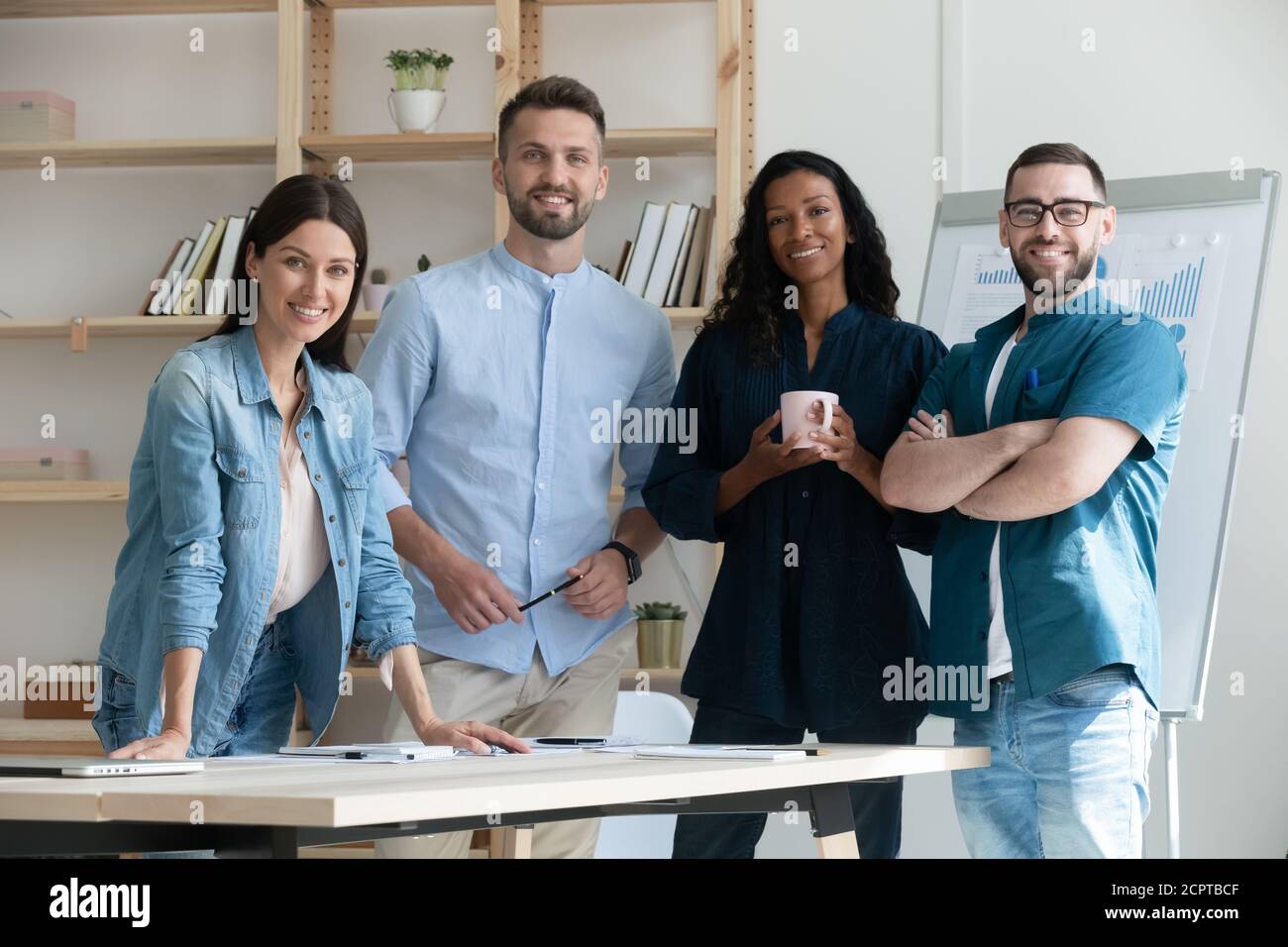 Smiling diverse employees standing in modern boardroom, group portrait ...
