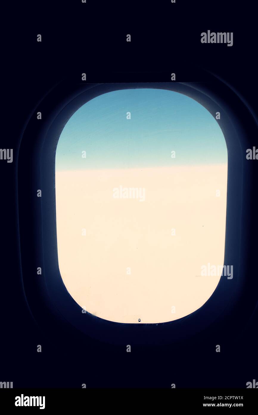 Airplane window with the interior in shadow and outside view of clouds ...