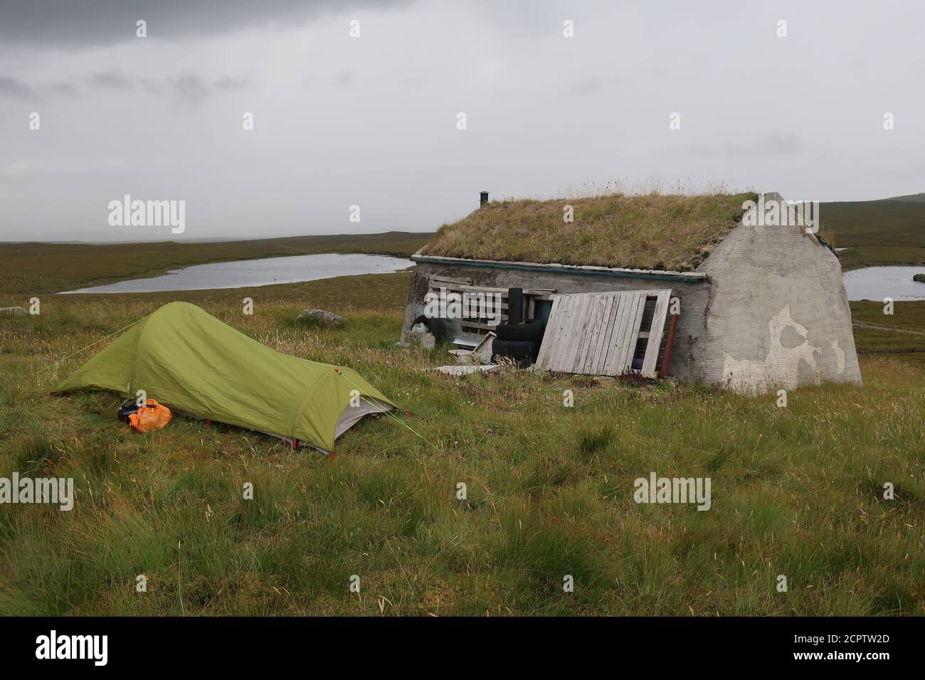 Wild camping in a tent by a Turfed roof bothy hut on The moors. The ...