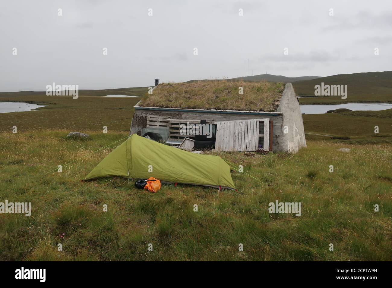 Wild camping in a tent by a Turfed roof bothy hut on The moors. The ...