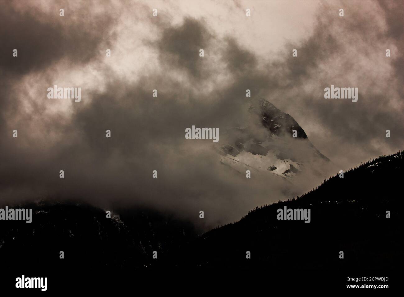 A mountain peak barely visible through the cloud breaks in a view ...