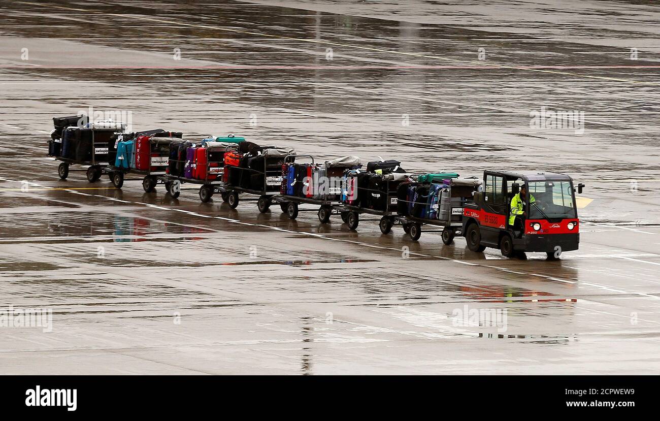 A tow tractor transports luggage on trailers of Swiss cargo handler ...