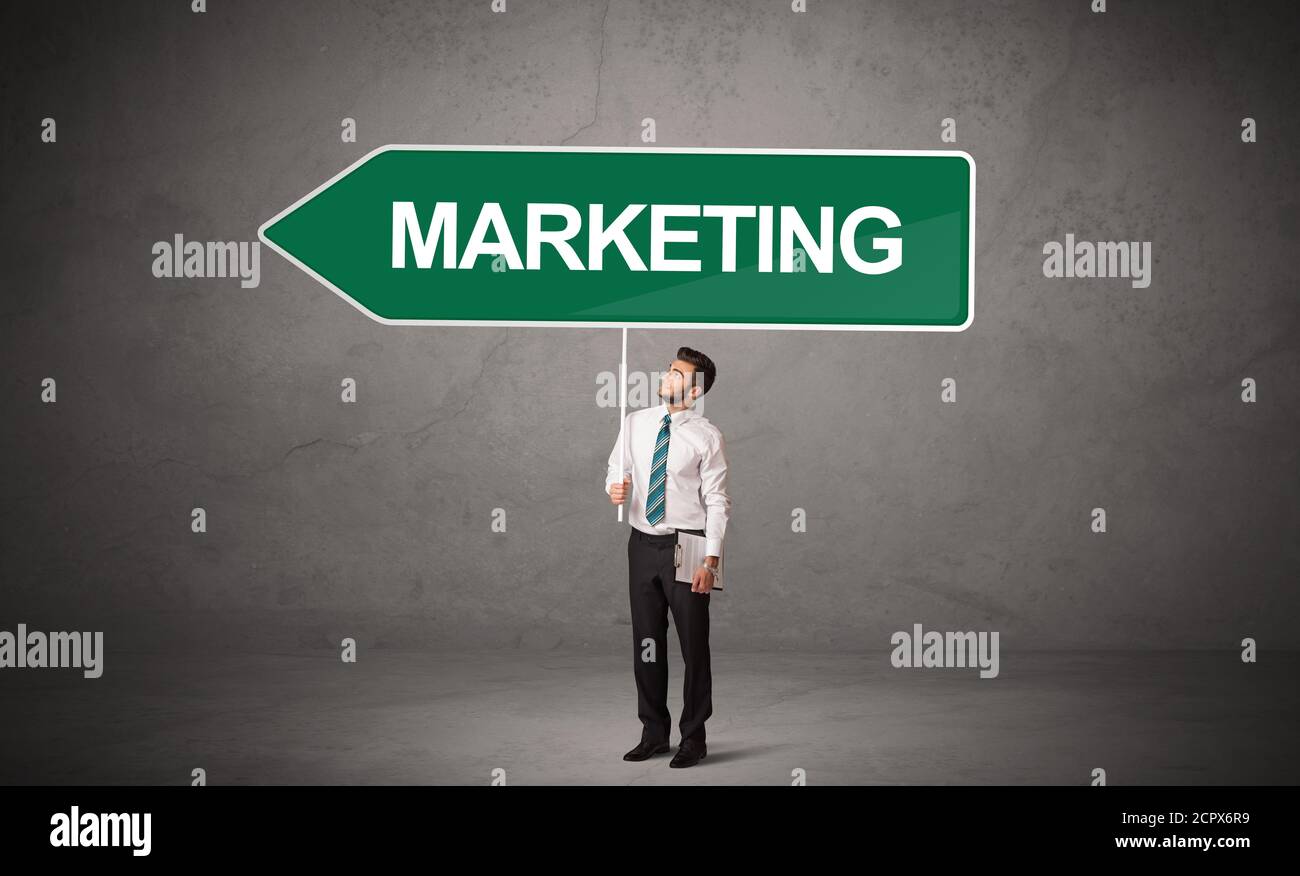 Young business person in casual holding road sign with MARKETING ...