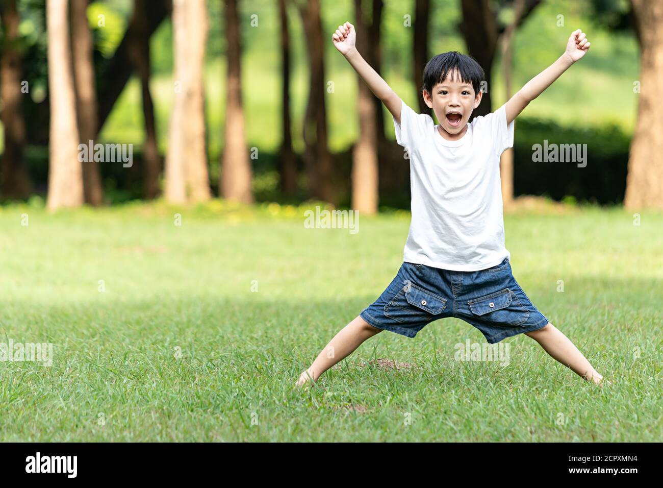 Portrait asian boy raising arms in the public park. The child was ...