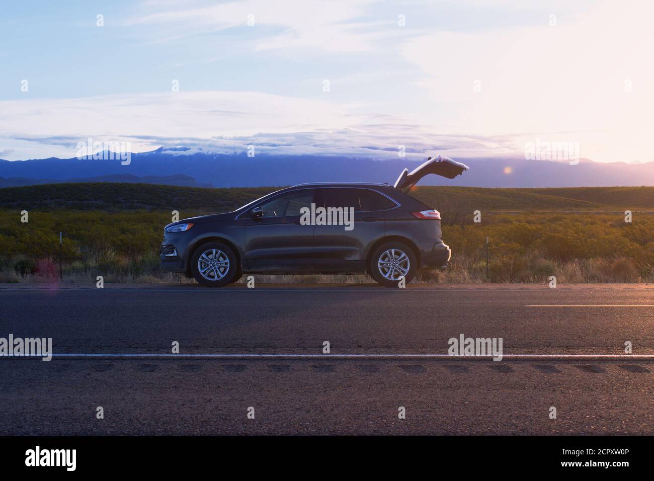 Morning light hitting car parked on the shoulder with trunk door open ...