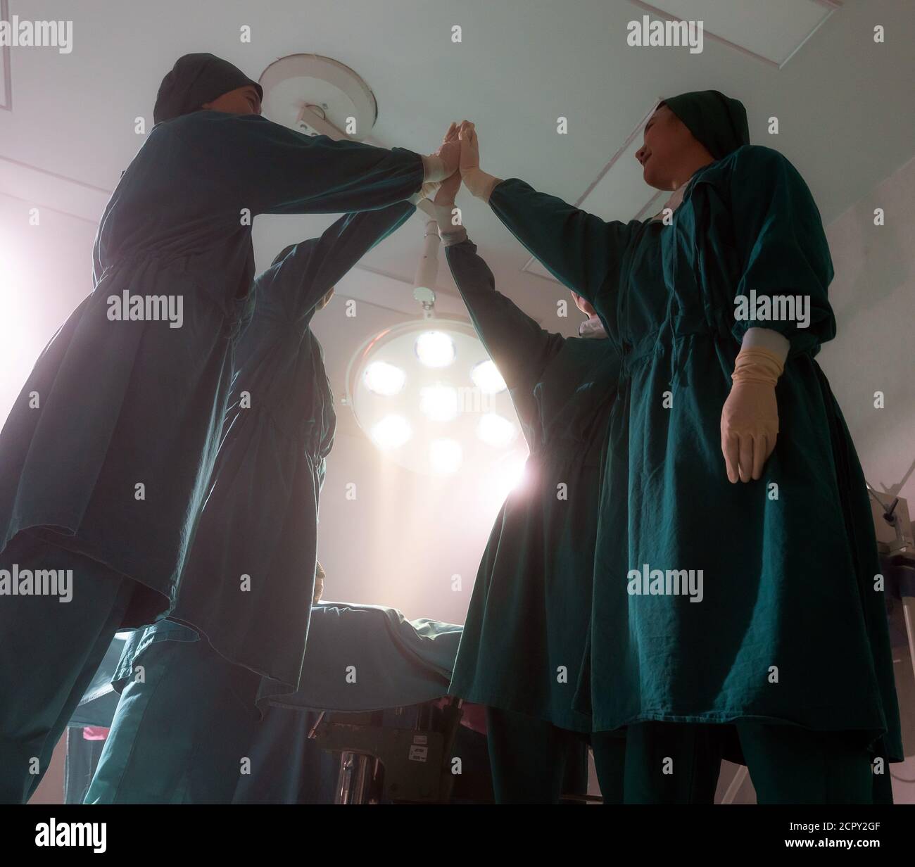 Asian surgeons team joining hands together cheering and celebrate after ...