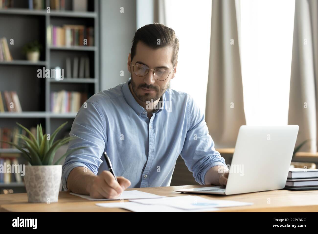 Man on computer making notes hi-res stock photography and images - Alamy