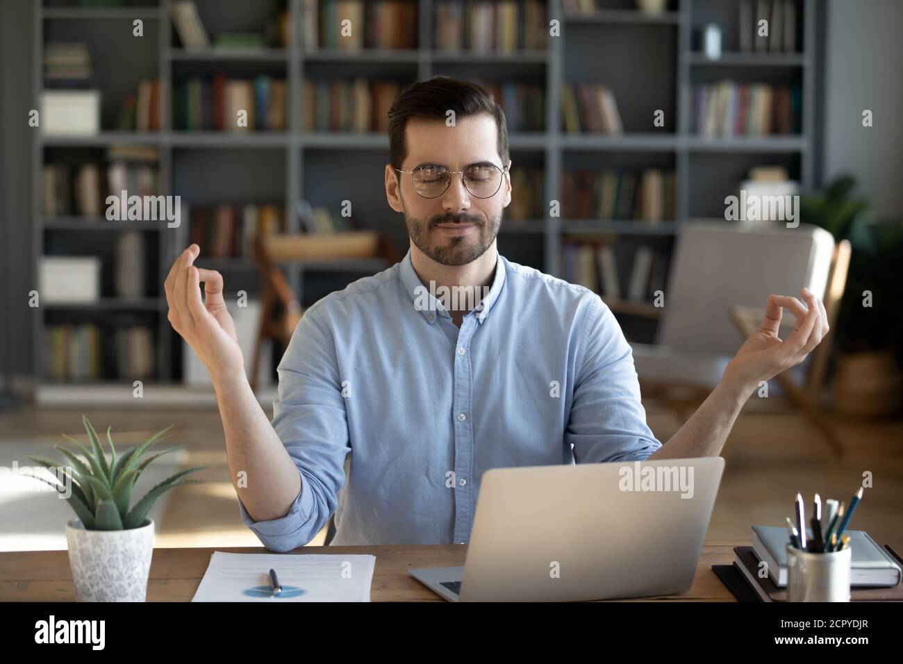 Calm Caucasian male worker meditate at workplace Stock Photo - Alamy