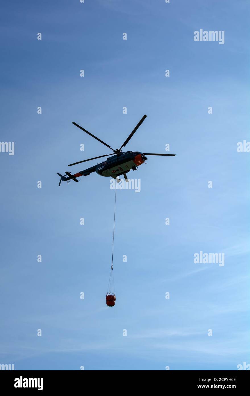 Mil Mi-17 helicopter flies in the sky carrying bucket of water for fire ...