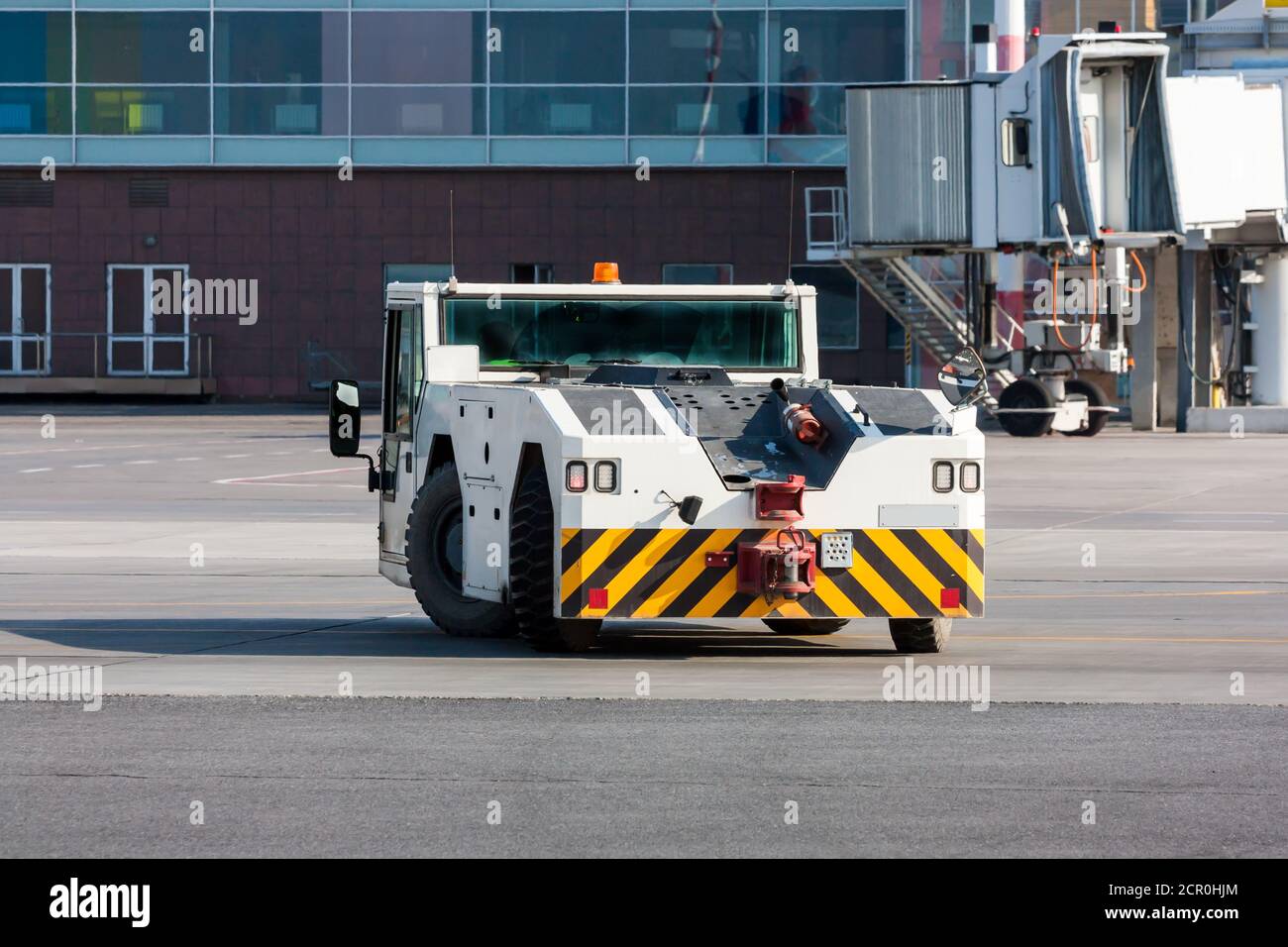 Airplane tow tractor near passenger boarding bridge Stock Photo - Alamy