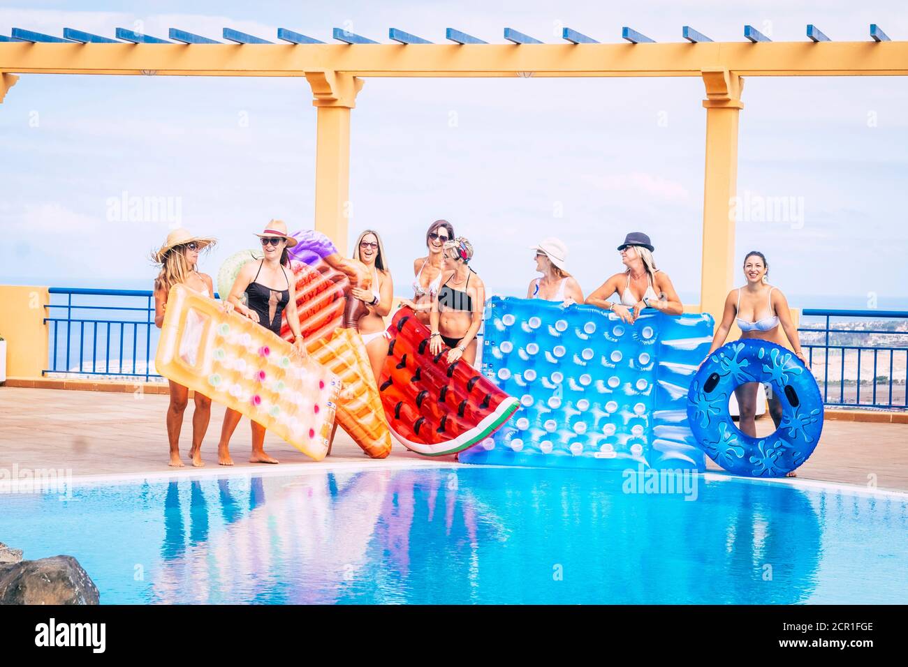 Happy young women have fun together enjoying the leisure at the pool ...