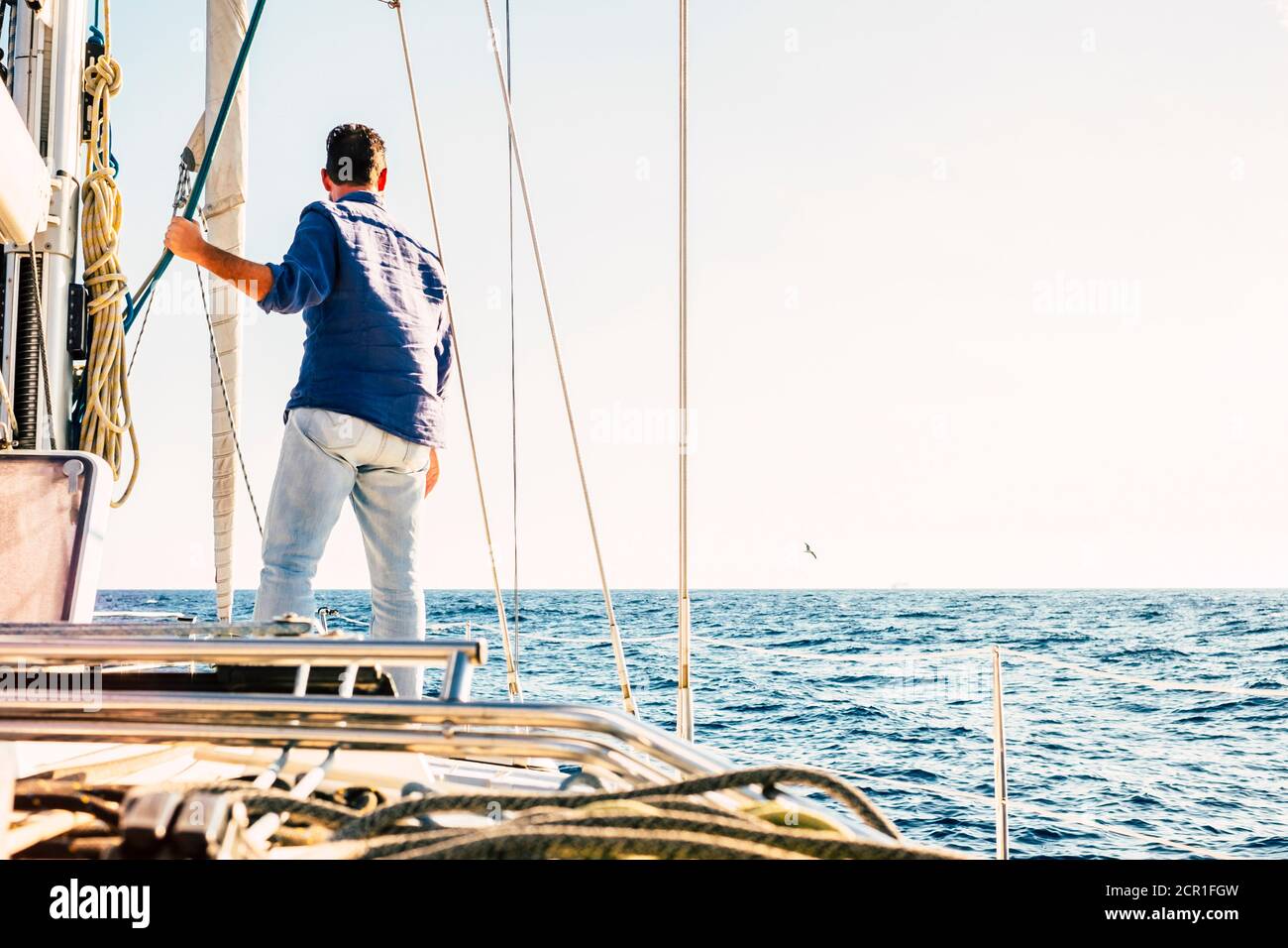 Sailing activity people - man viewed from back stand up on the deck of ...
