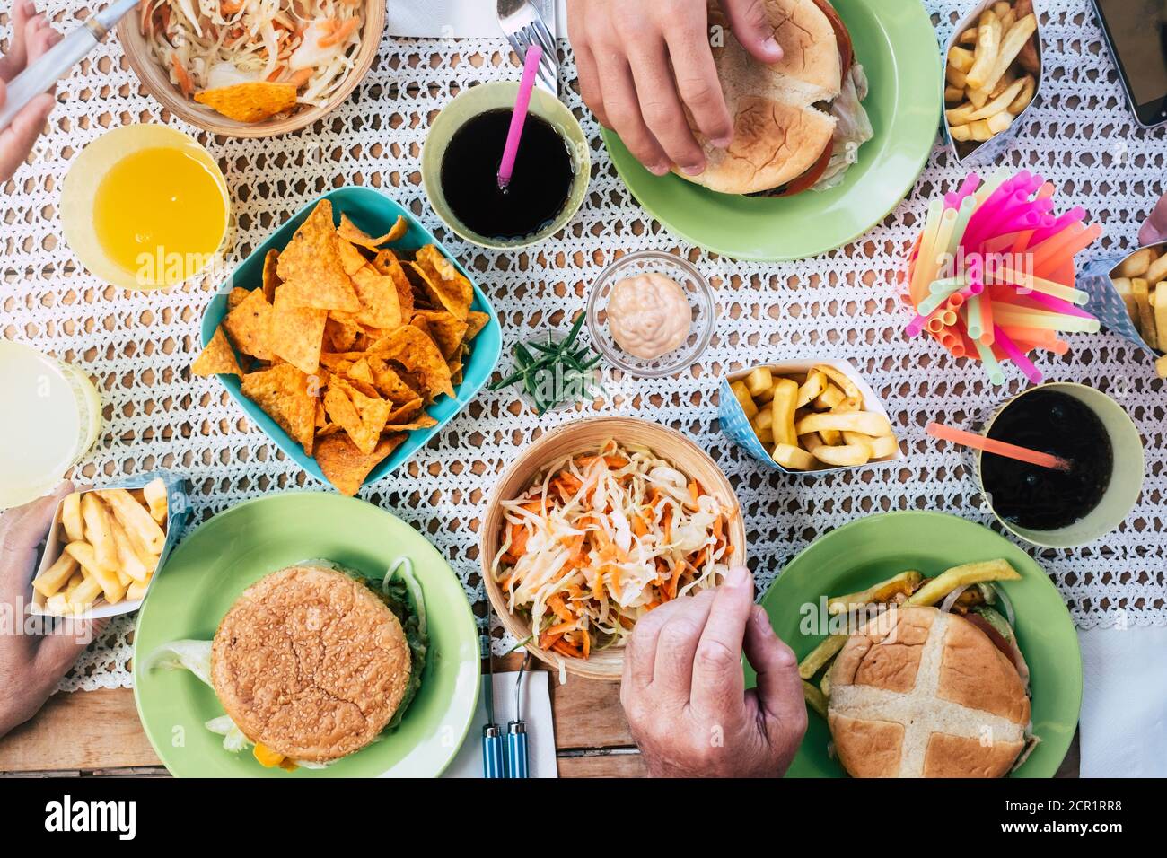 Vertical table view with people eating junk hamburger food together ...