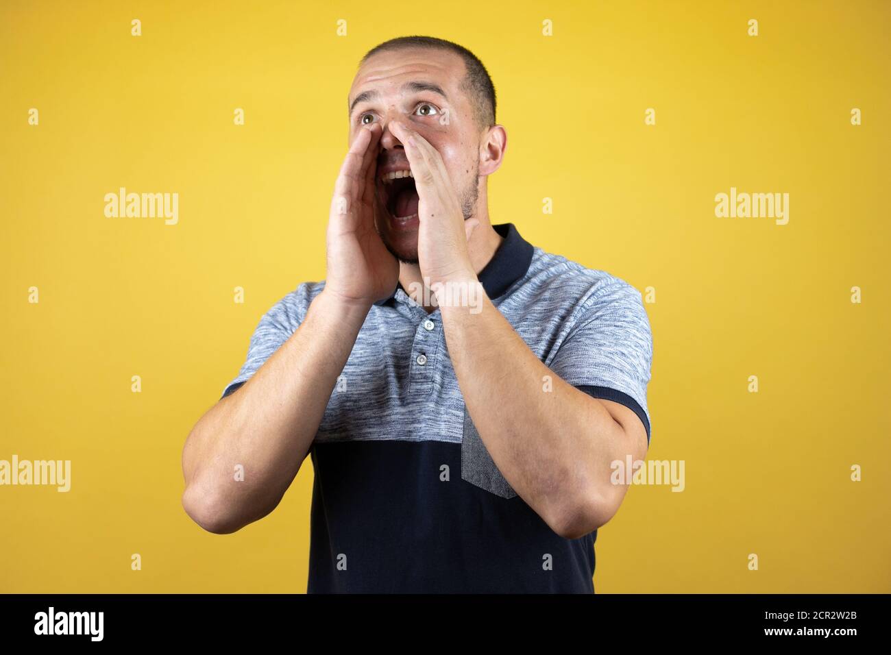 Russian man standing over insolated yellow background shouting and ...