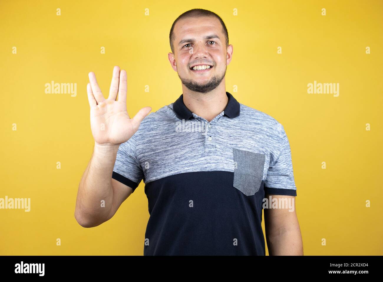 Russian man standing over insolated yellow background doing star trek ...