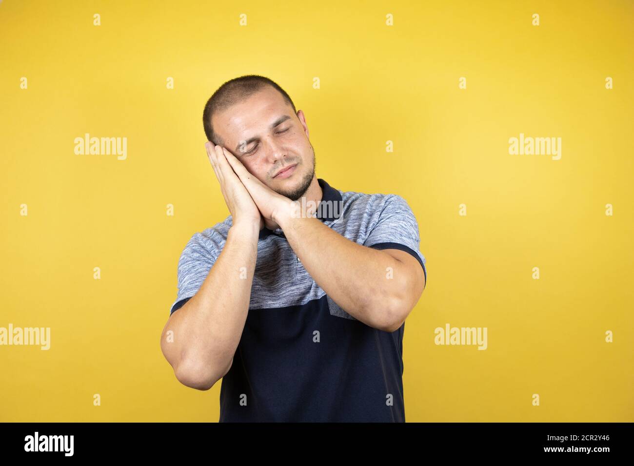 Russian man standing over insolated yellow background sleeping tired ...
