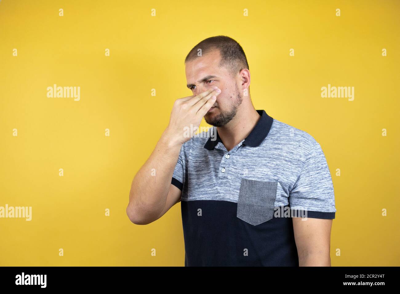 Russian man standing over insolated yellow background smelling ...
