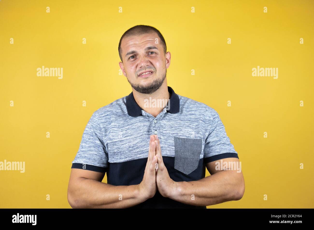 Russian man standing over insolated yellow background begging and ...