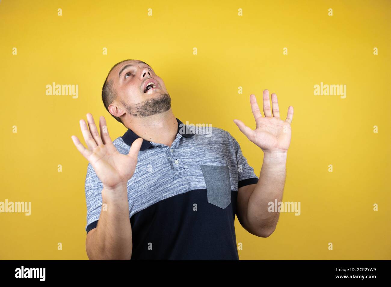 Russian man standing over insolated yellow background scared with her ...