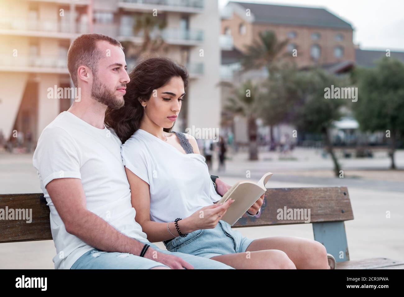 Young Caucasian couple sitting on a bench and reading a book Stock ...