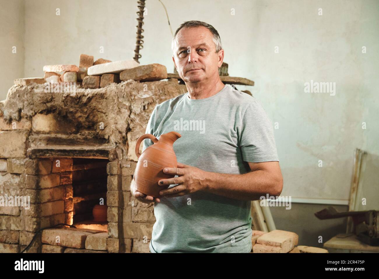 Master potter stands near pottery kiln and show his product Stock Photo ...