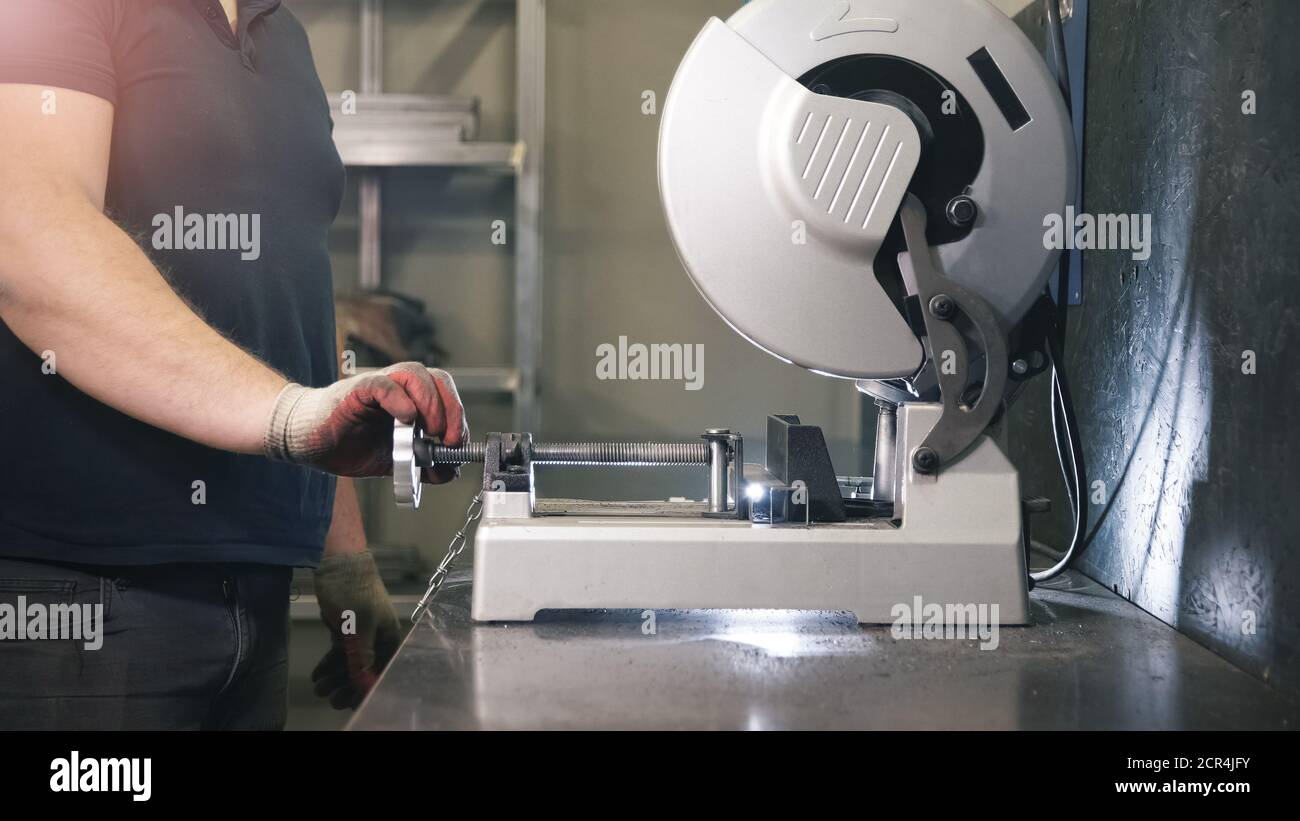 Metal grinding machine in work. Worker sawing steel. Manufacturing ...