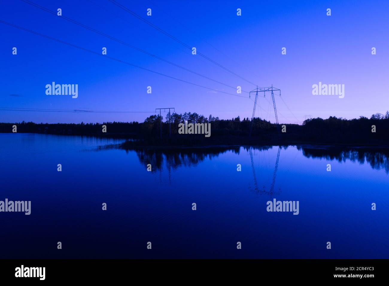 Lake in front of high-voltage powerline pylons Stock Photo - Alamy