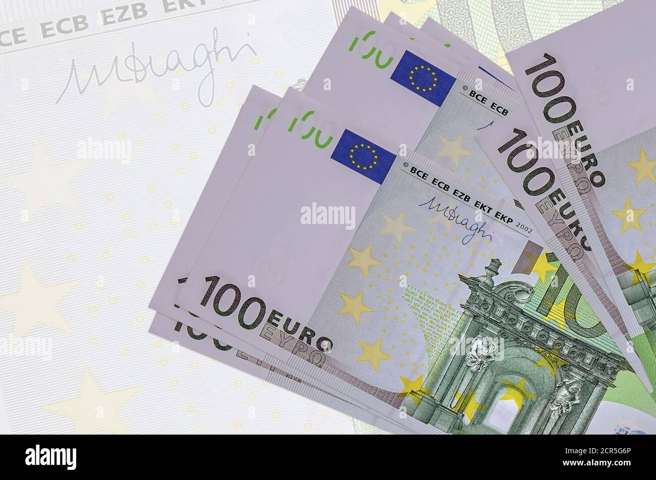 100 Euro bills lies in stack on background of big semi-transparent banknote. Abstract ...
