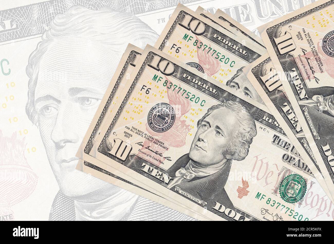 10 US dollars bills lies in stack on background of big semi-transparent ...