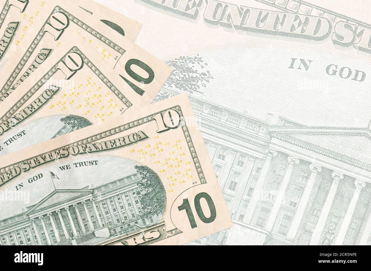 10 US dollars bills lies in stack on background of big semi-transparent ...