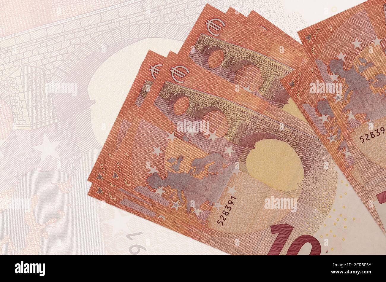 10 euro bills lies in stack on background of big semi-transparent banknote. Abstract ...