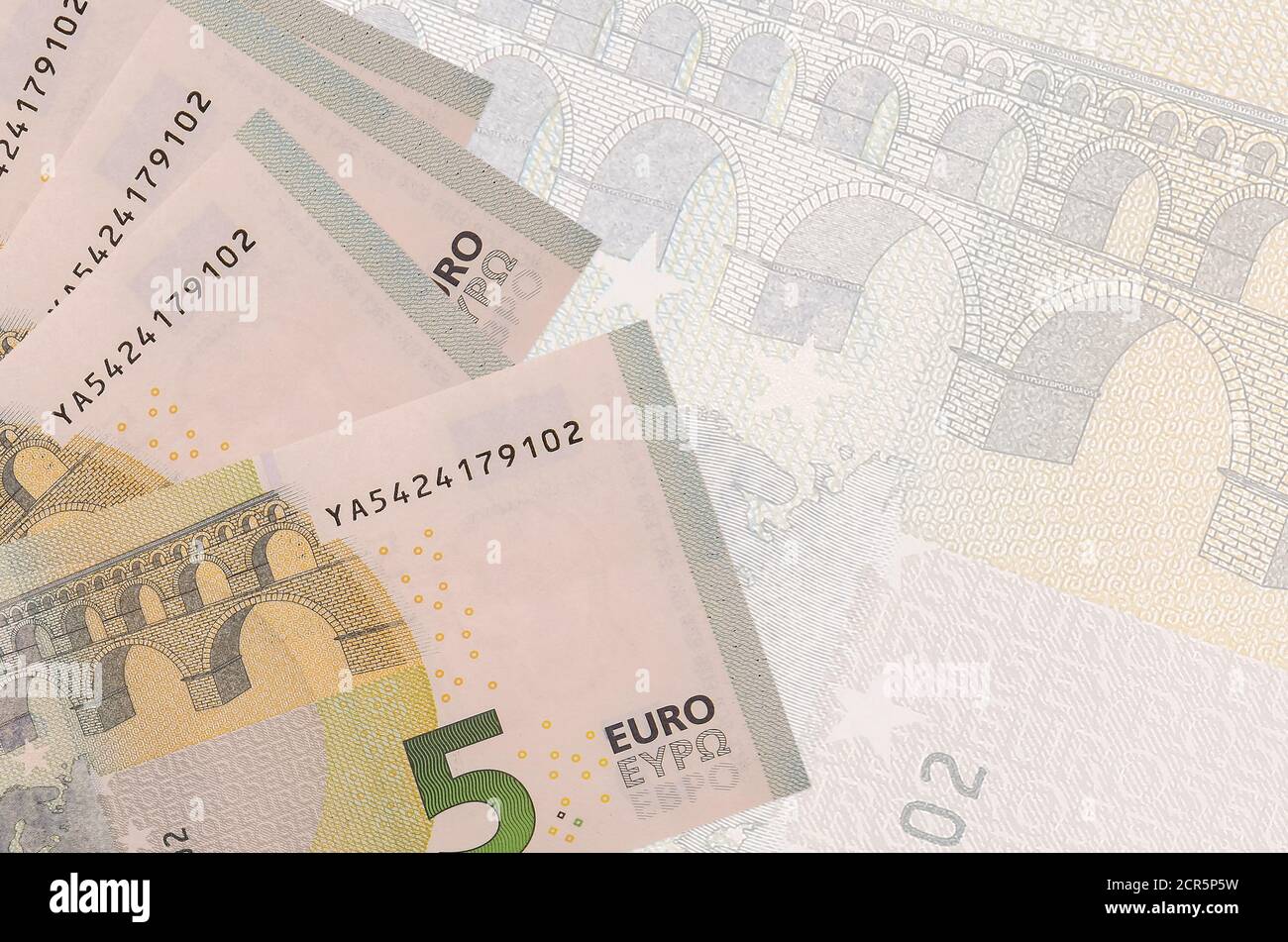 5 euro bills lies in stack on background of big semi-transparent banknote. Abstract business ...