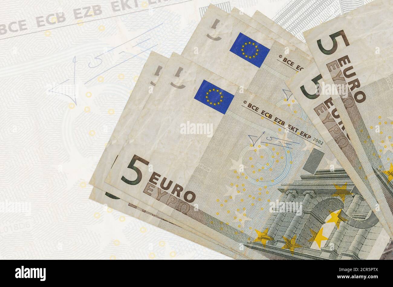 5 euro bills lies in stack on background of big semi-transparent banknote. Abstract presentation ...