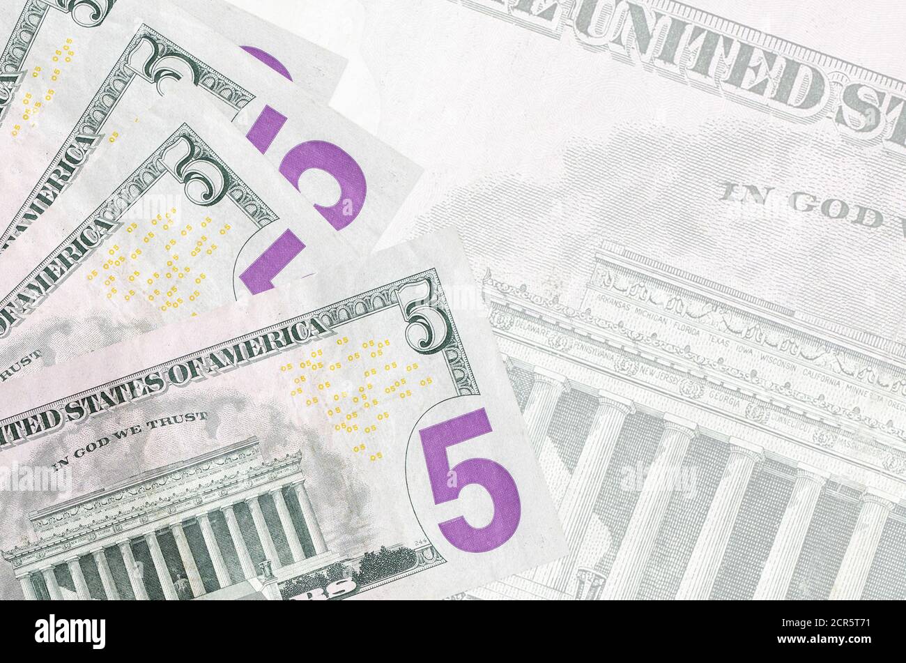 5 US dollars bills lies in stack on background of big semi-transparent ...
