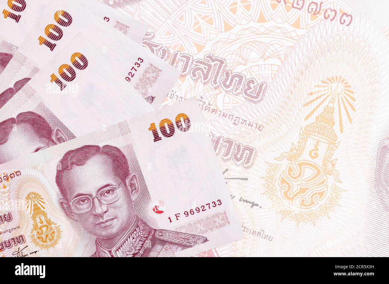 100 Thai Baht bills lies in stack on background of big semi-transparent ...