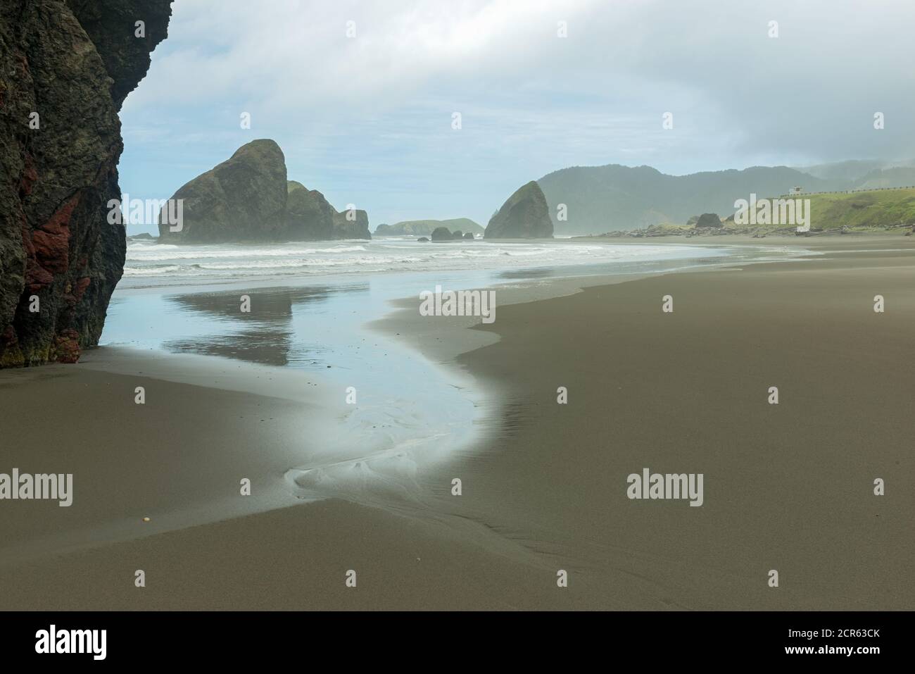 Water washing over the sandy beach between the sea stacks on the ...