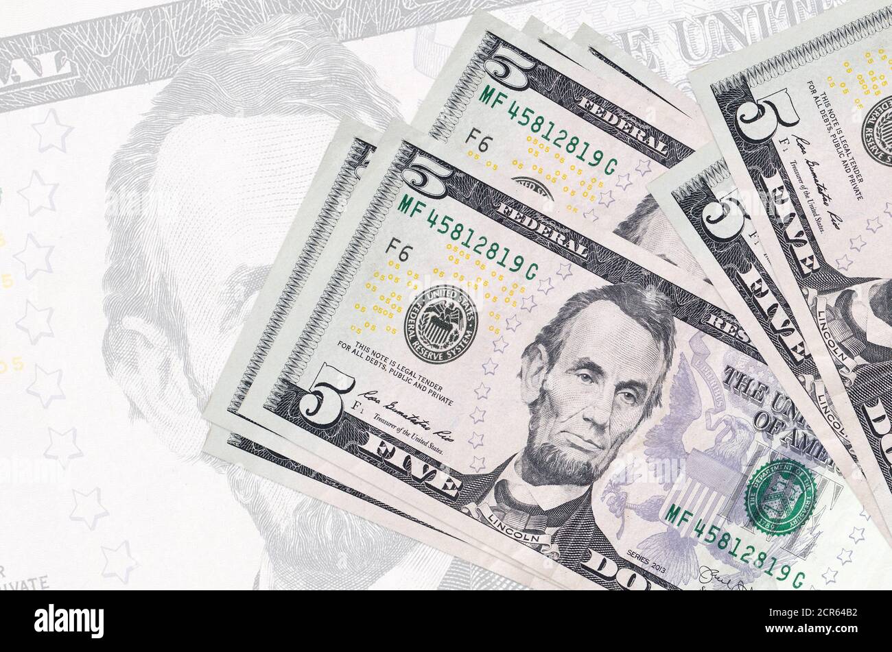 5 US dollars bills lies in stack on background of big semi-transparent ...