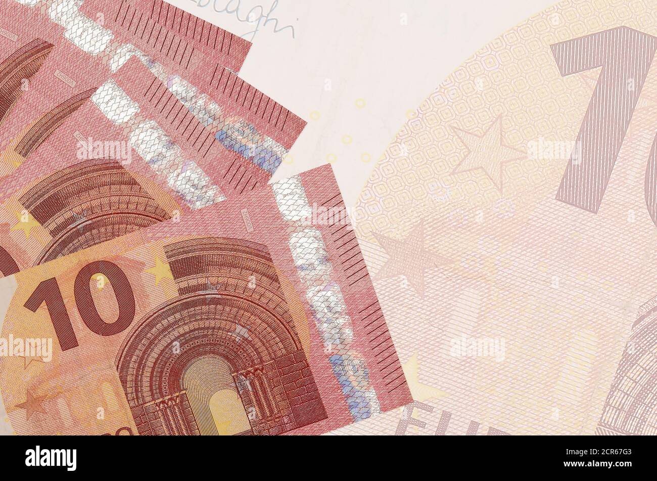 10 euro bills lies in stack on background of big semi-transparent banknote. Abstract business ...