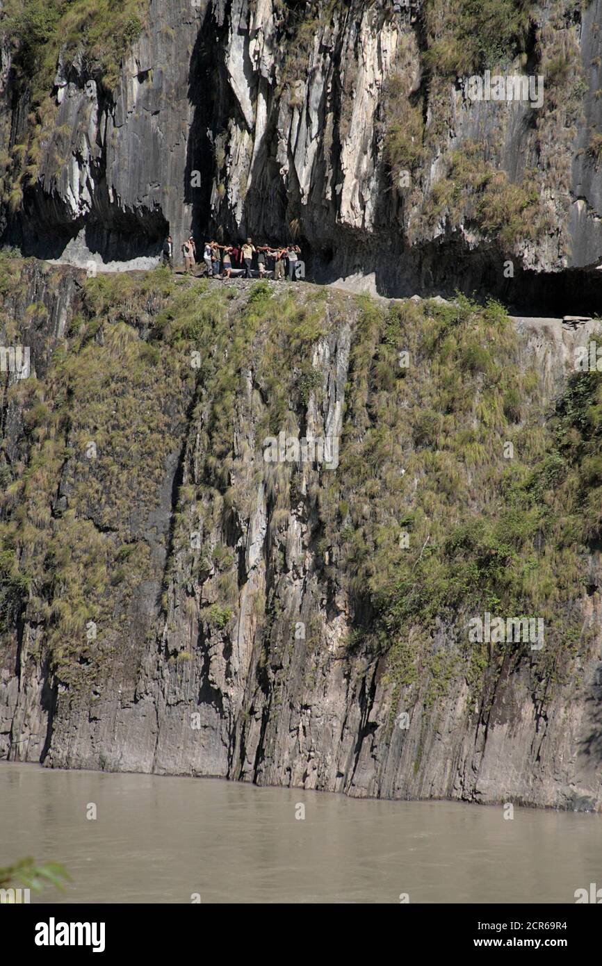 People using a footpath carved into vertical cliff, above Nujiang ...