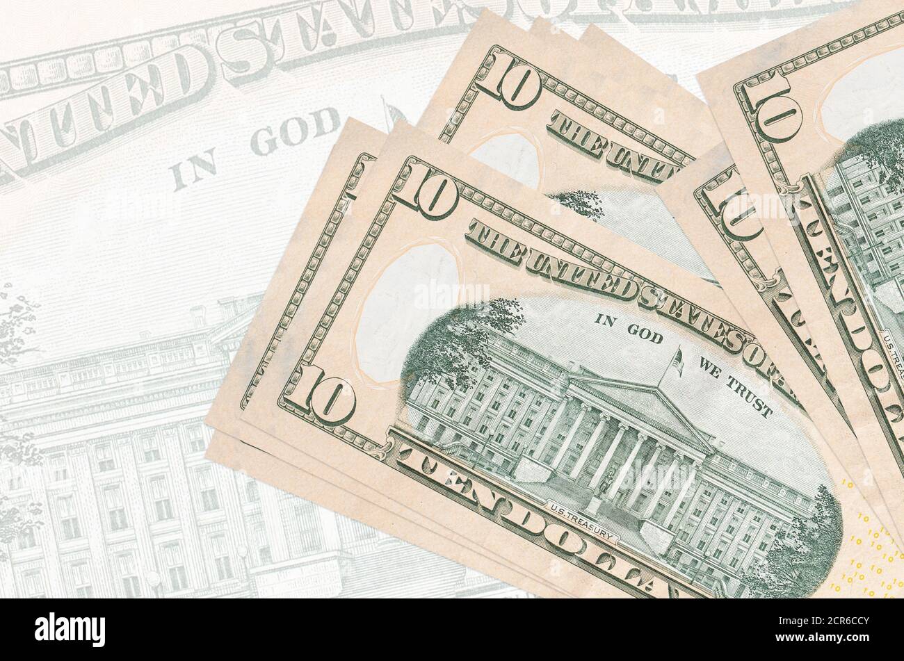 10 US dollars bills lies in stack on background of big semi-transparent ...