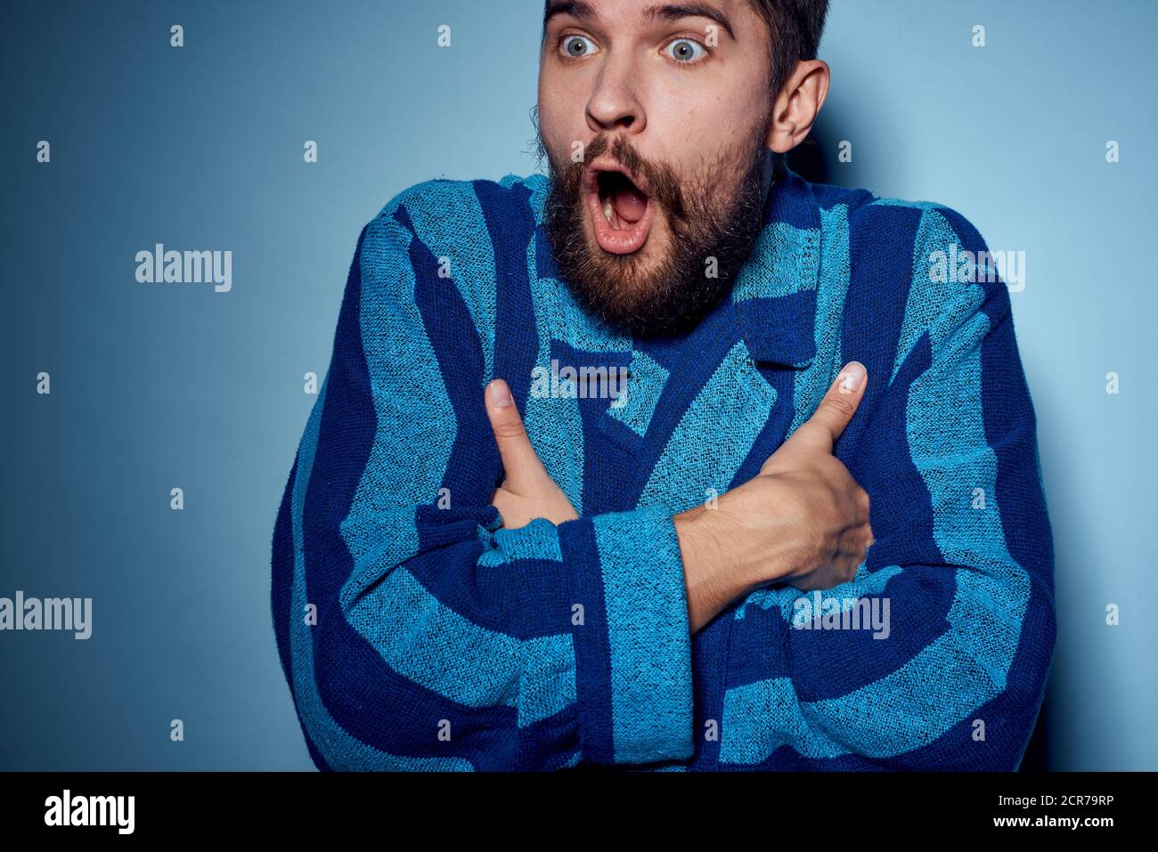 A man in a blue robe on a light background gestures with his hands ...