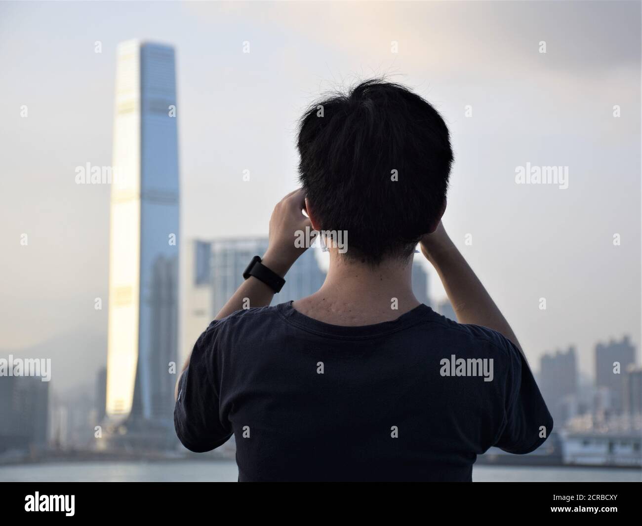 Asian guy seen from the back taking photo shoots of the buildings and ...