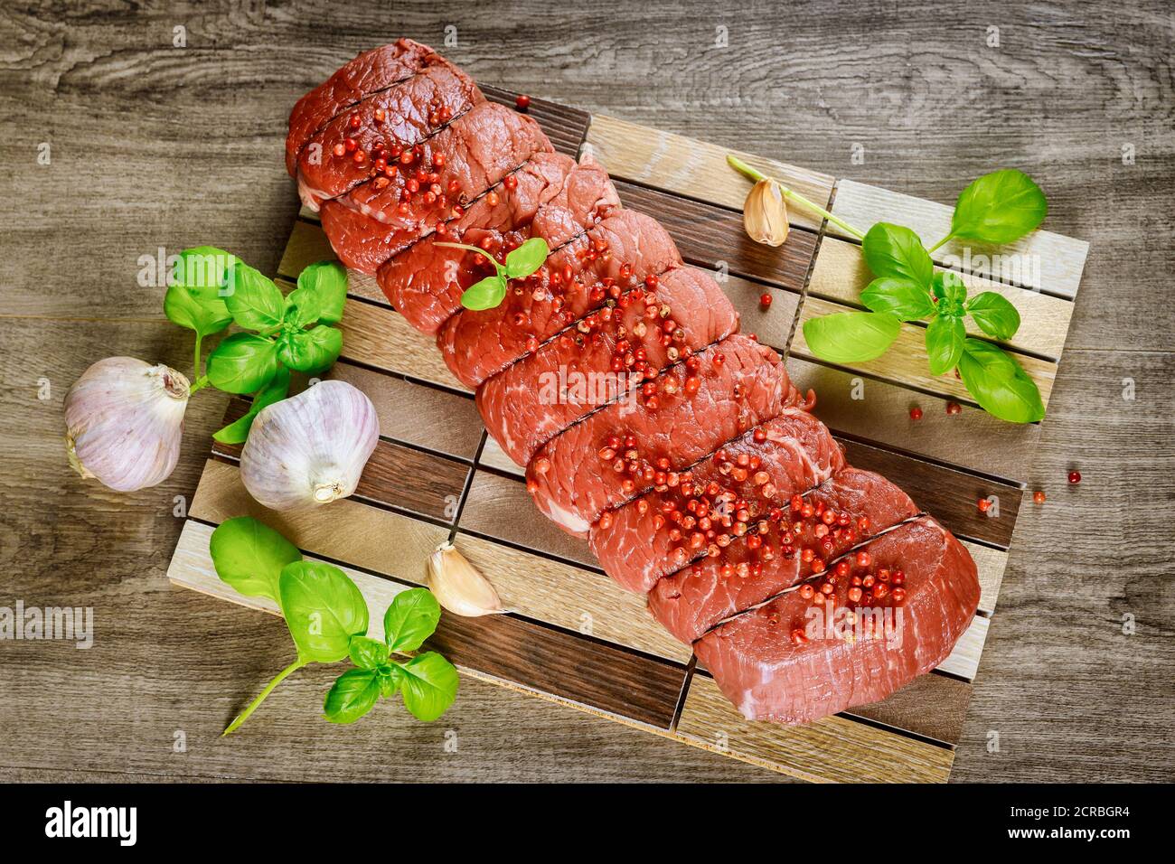 Raw rib eye beef steak with garlic and herbs on a wooden background ...