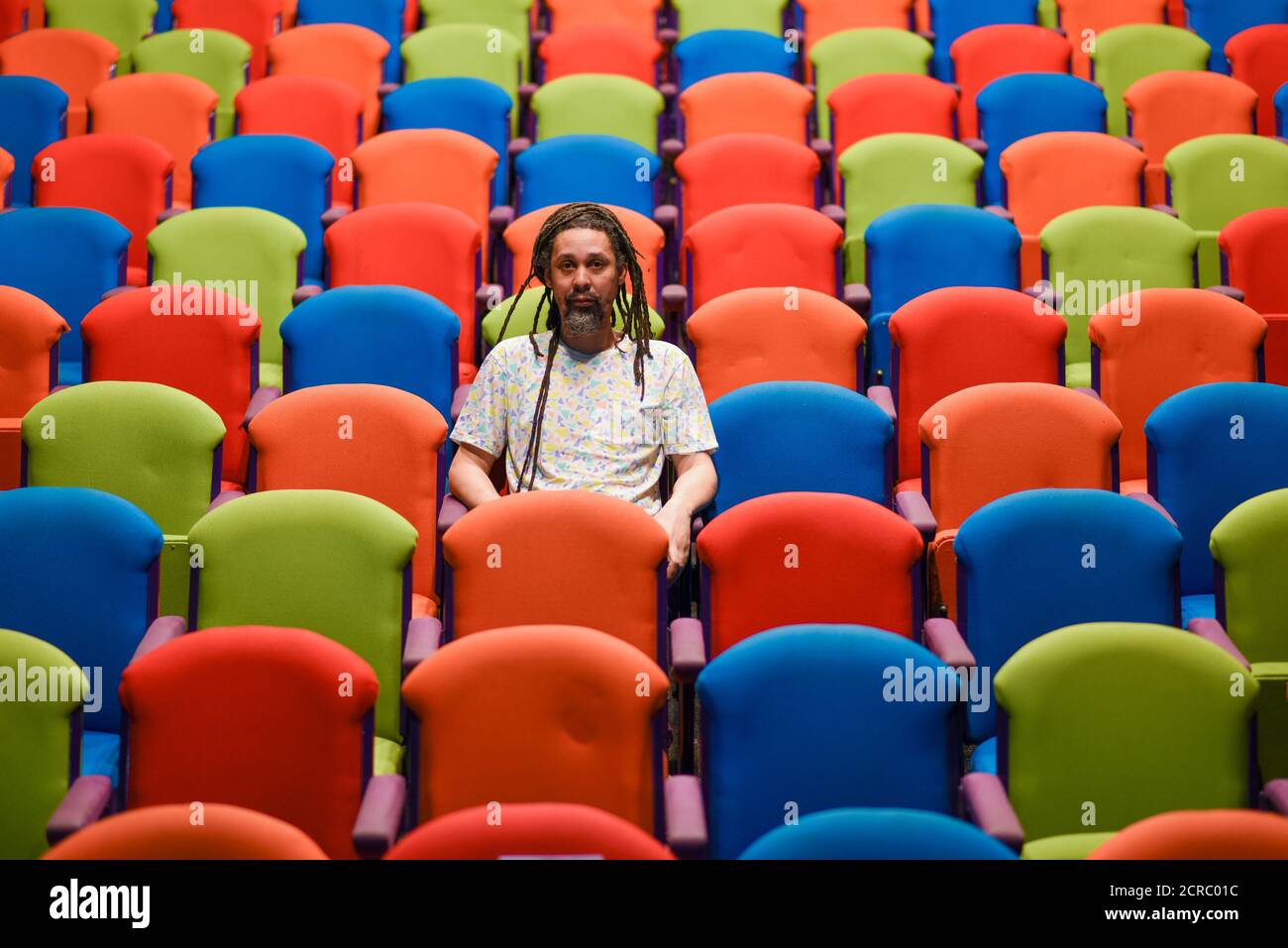 Colorful chairs with one person sitting on chair Stock Photo - Alamy