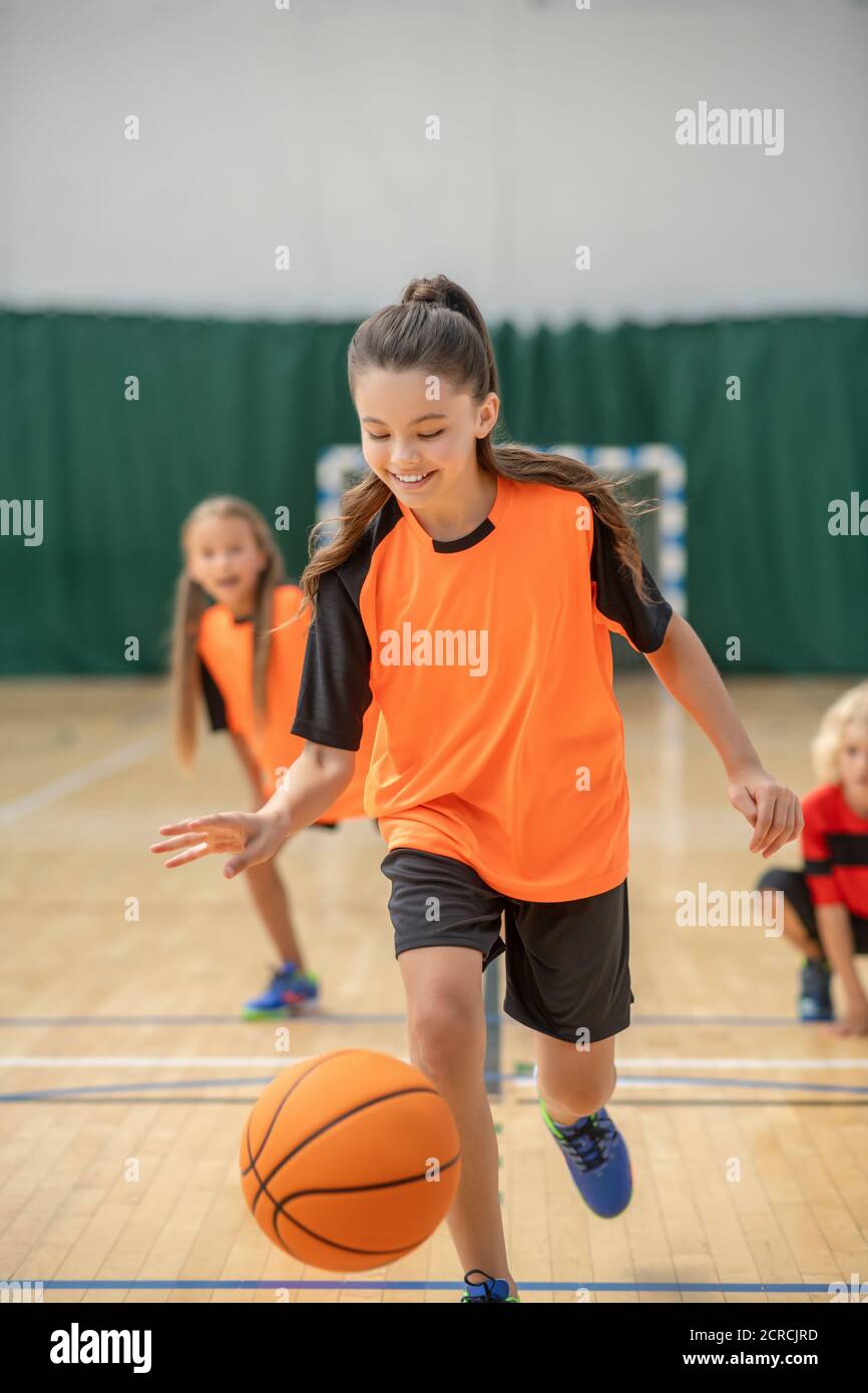 A girl running with a ball and looking involved Stock Photo - Alamy