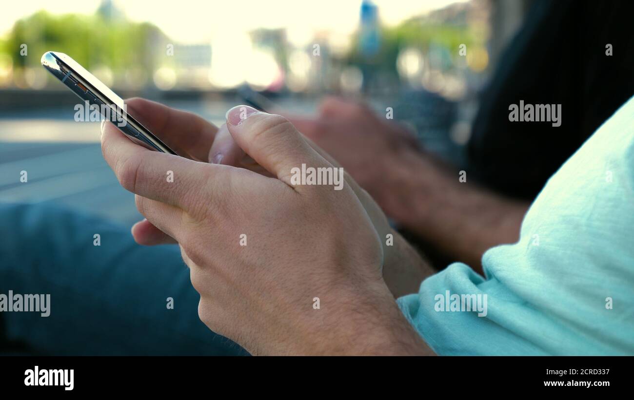 Men using their mobile phones sitting on a bench Stock Photo - Alamy
