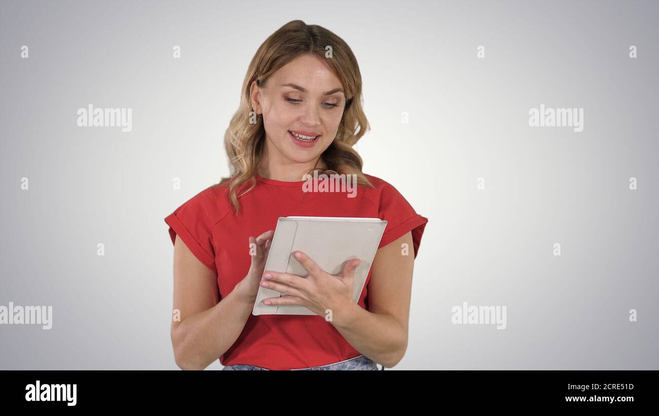 Blonde woman in red holding tablet and reading to camera from it Stock ...